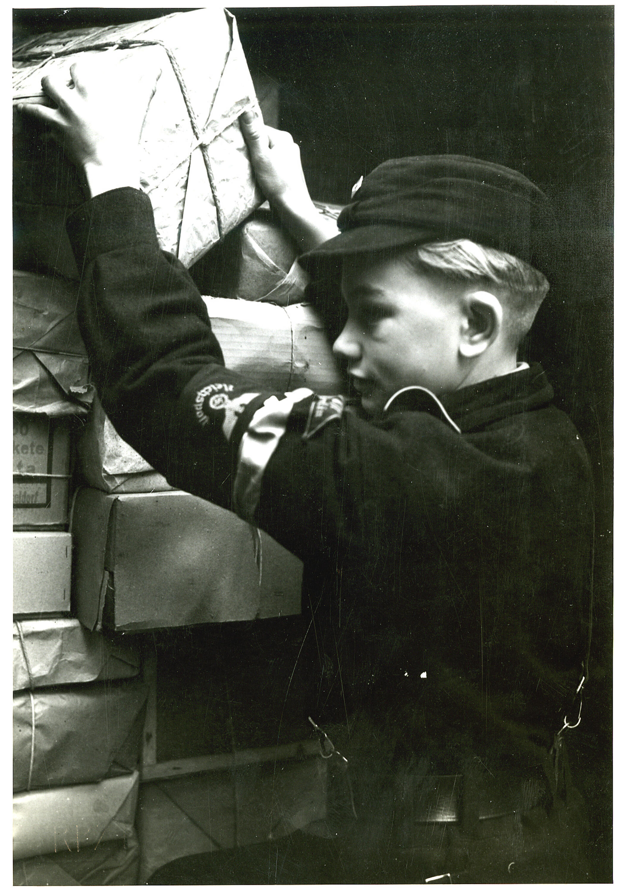 Fotografie, Junge in Uniform der Hitlerjugend beim Einstapeln von ...